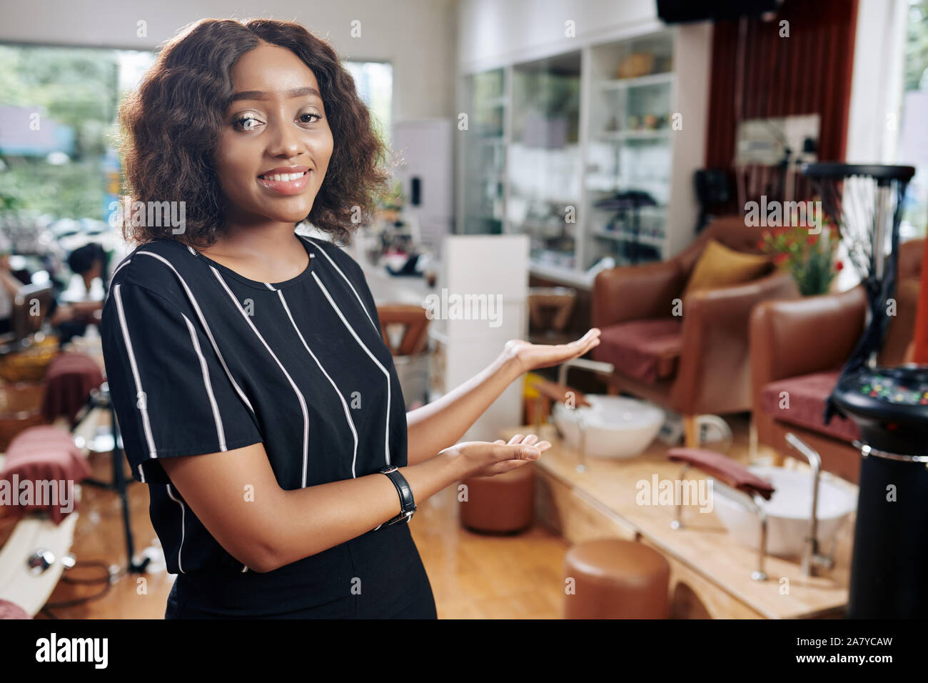 Beautiful young hair salon owner making welcoming gesture to invite ...