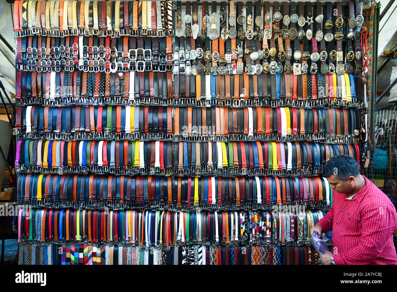 A foreign street vendor in front of his market stall of colorful ...