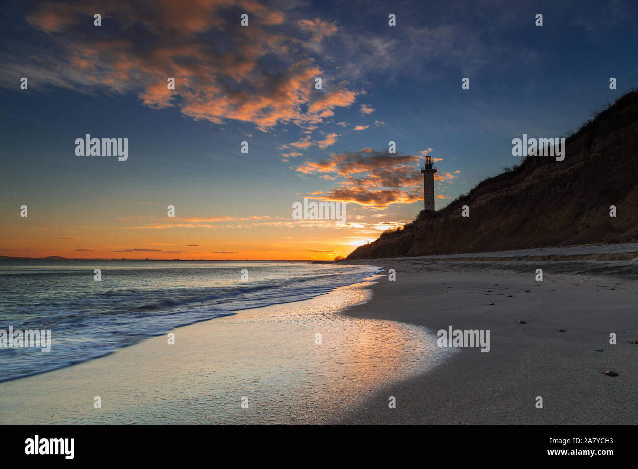 Sea lighthouse on the rocks at sunset Stock Photo - Alamy