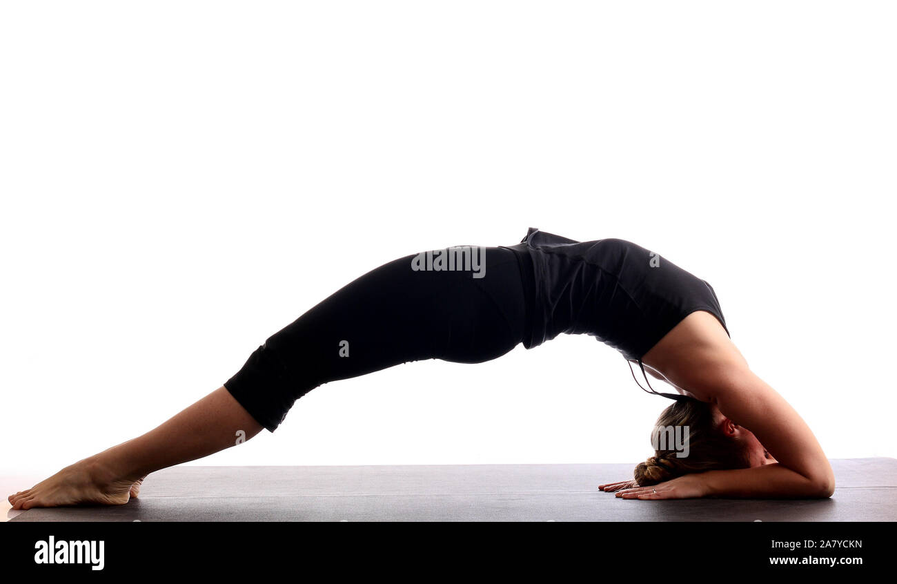 Young beautiful yoga female posing on a studio background. Standing in ...