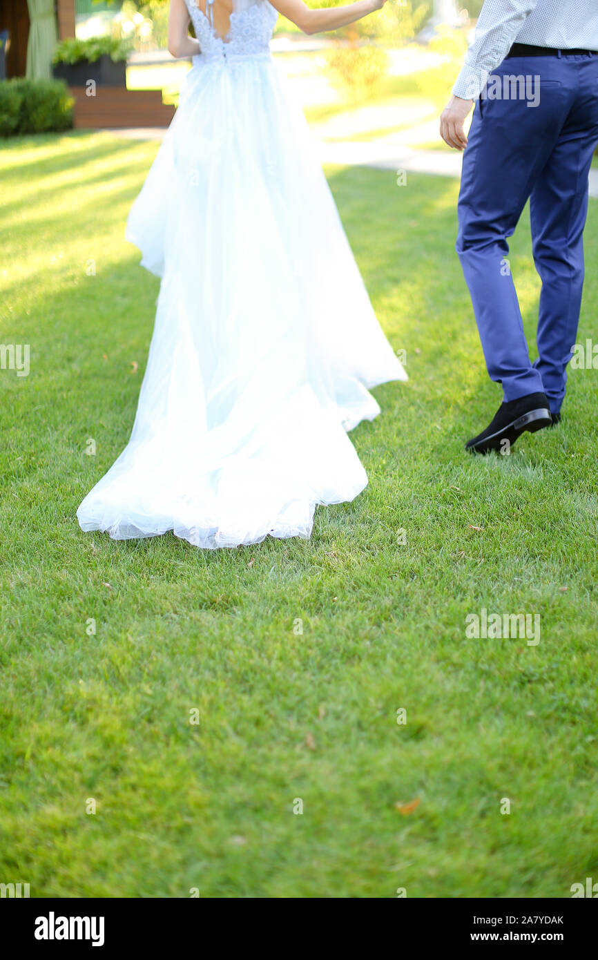 Back view of bride and groom walking in park on green grass Stock Photo ...