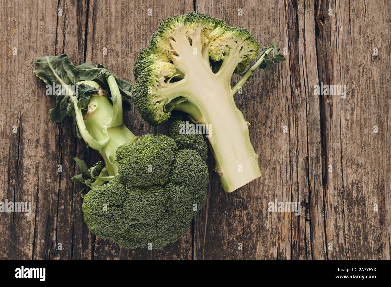 Broccoli, one cut in half, resting on an old table, matte style Stock ...