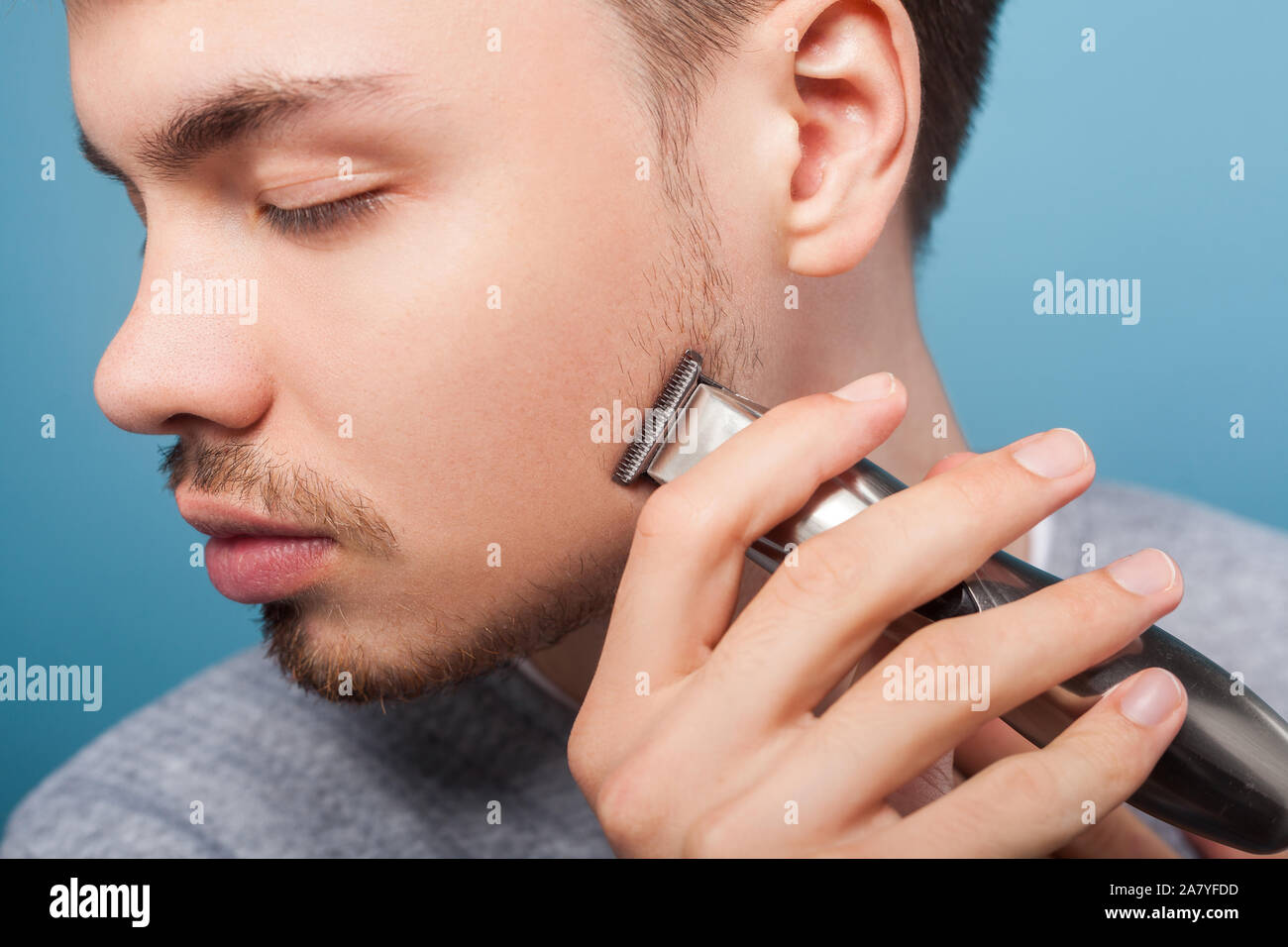 Daily shaving routine. Closeup portrait of young man grooming cheek ...