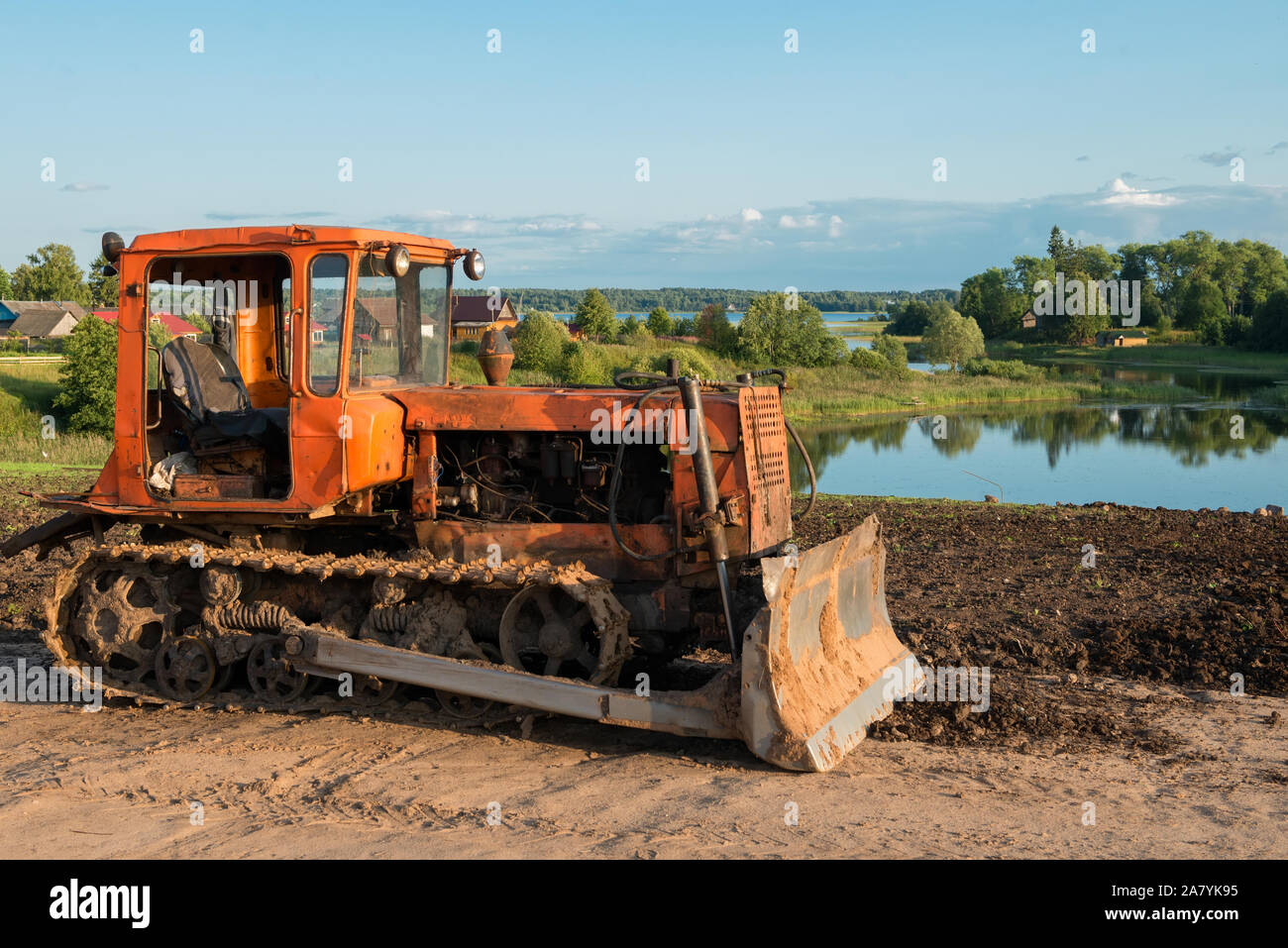 Caterpillar agricultural tractor DT-75 in the countryside, on the lake ...