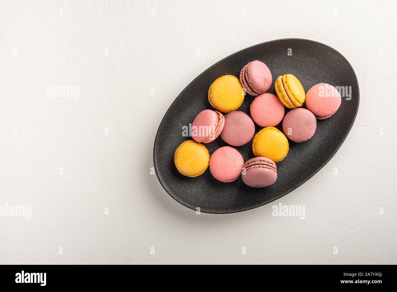Colorful French or Italian macaron stack on dark plate put on white ...