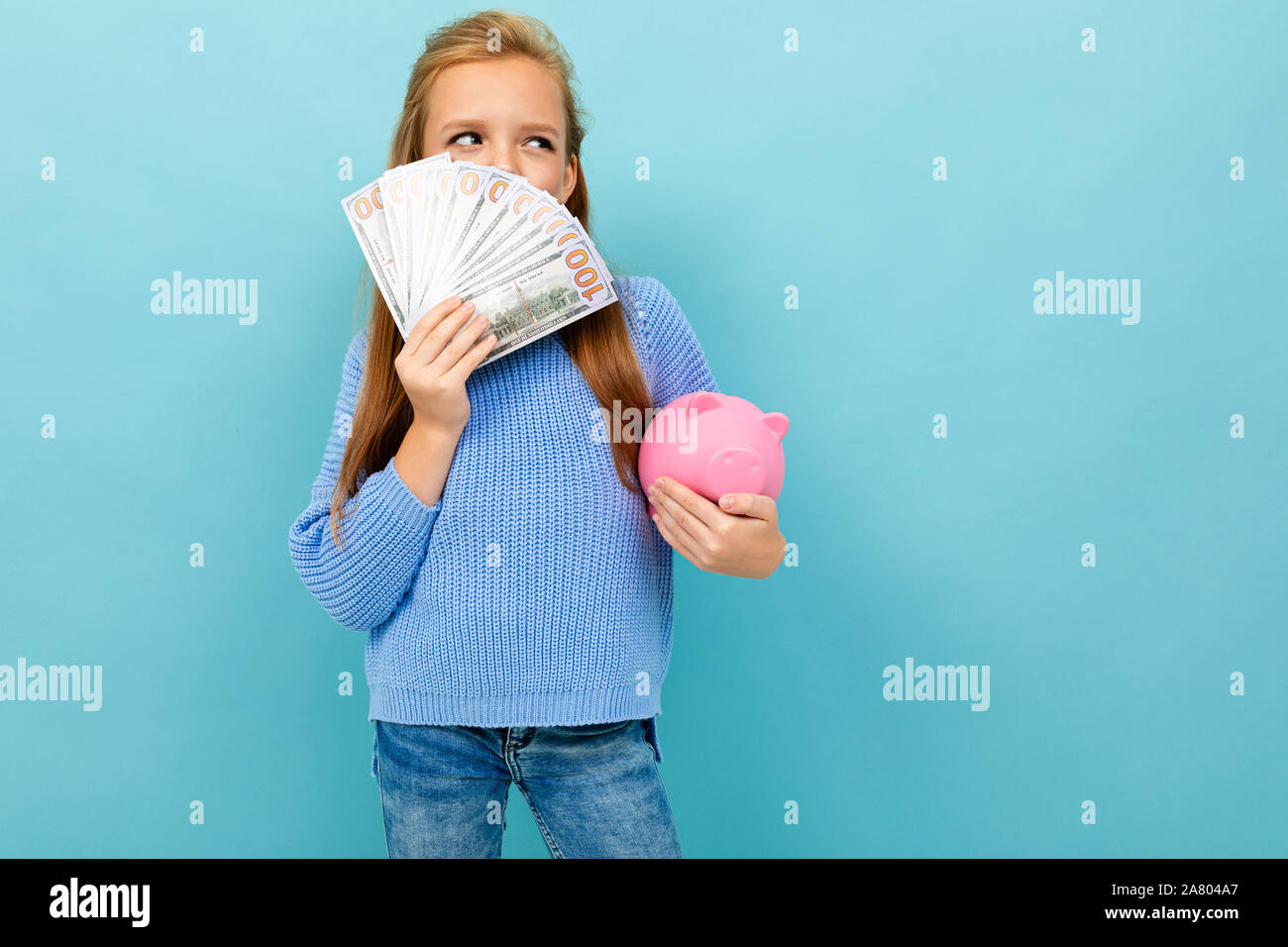 excited contented girl on a blue background with a fan of money and a ...