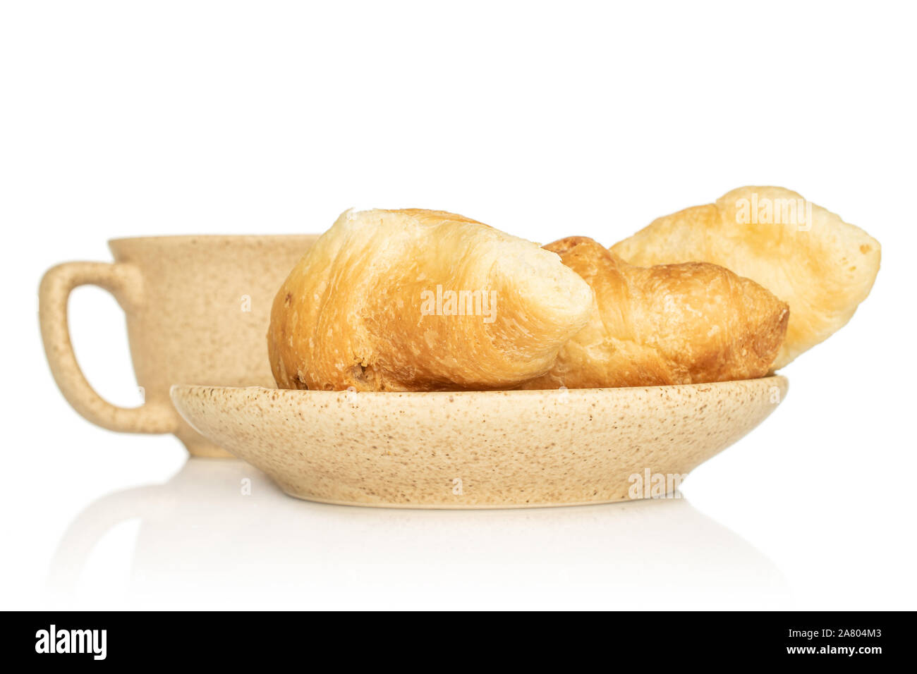 Group of three whole fresh baked mini croissant with saucer and cup ...