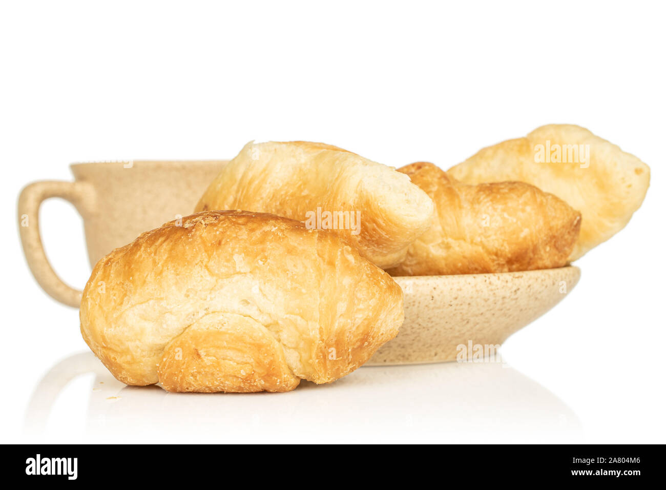 Group of four whole fresh baked mini croissant with cup isolated on ...