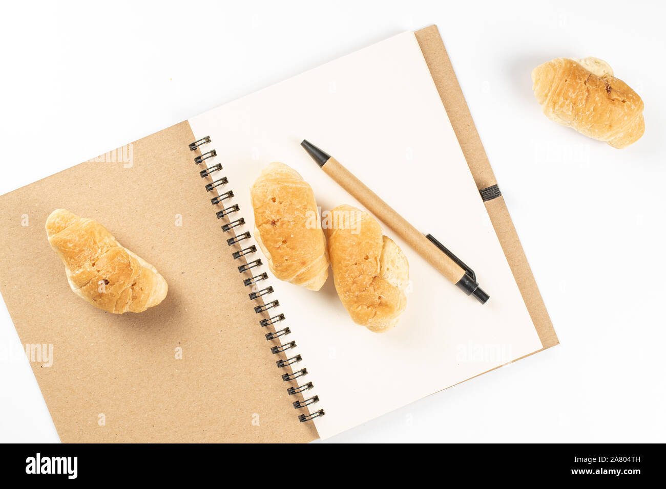 Group of four whole fresh baked mini croissants on notebook with pen ...