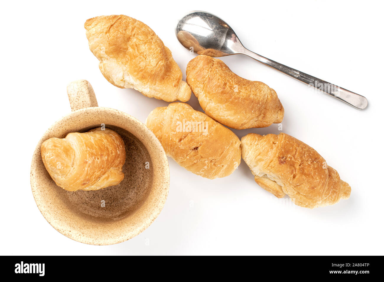 Group of five whole fresh baked mini croissant with cup and steel spoon ...