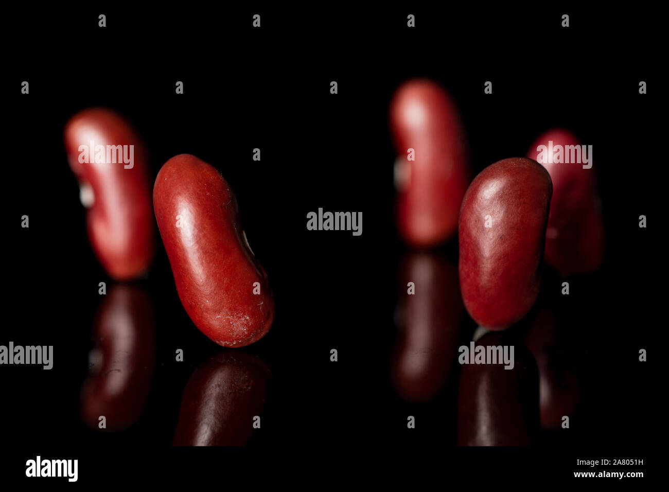 Group of five whole fresh red kidney beans isolated on black glass ...