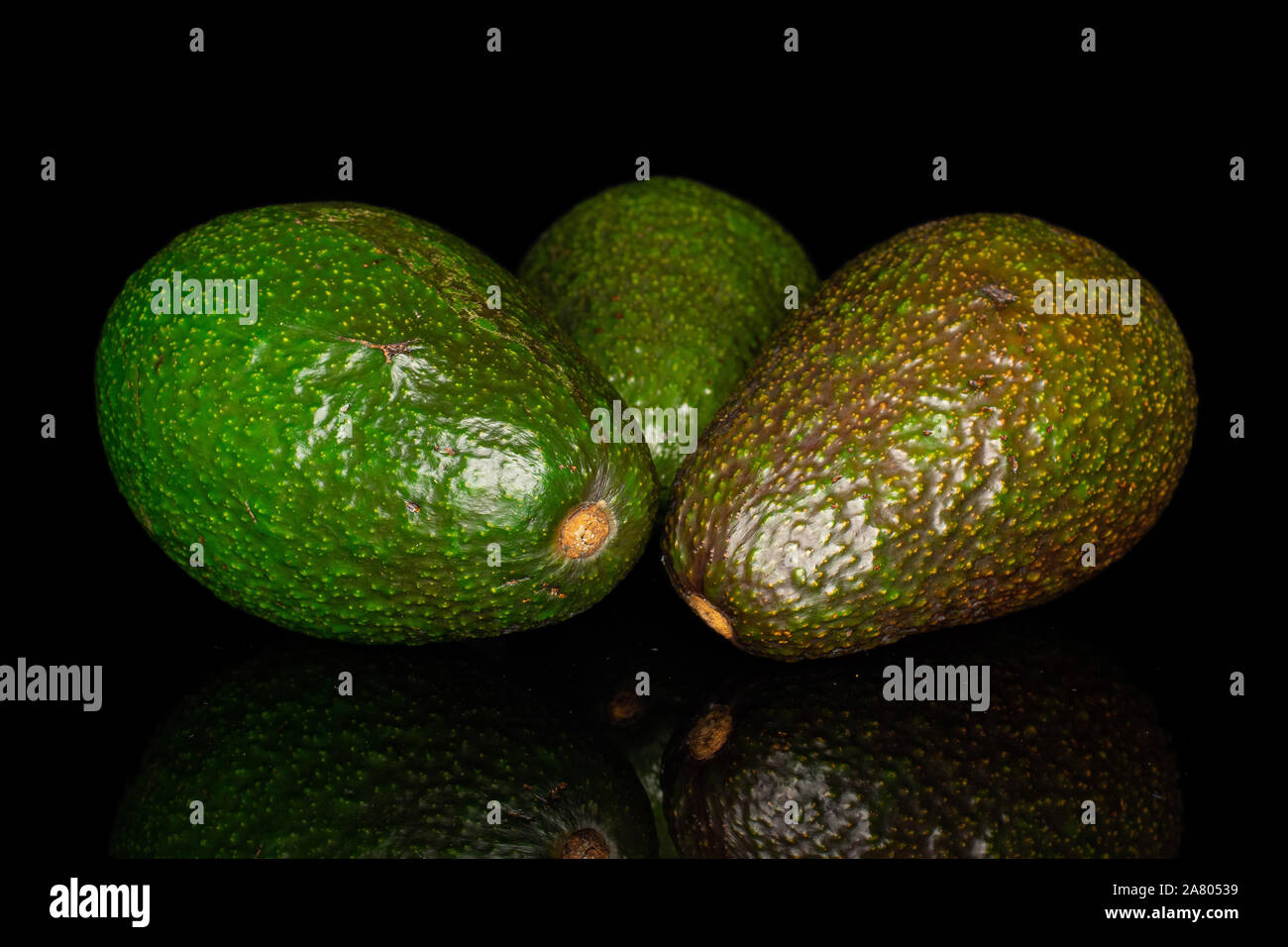Group of three whole fresh green avocado isolated on black glass Stock ...