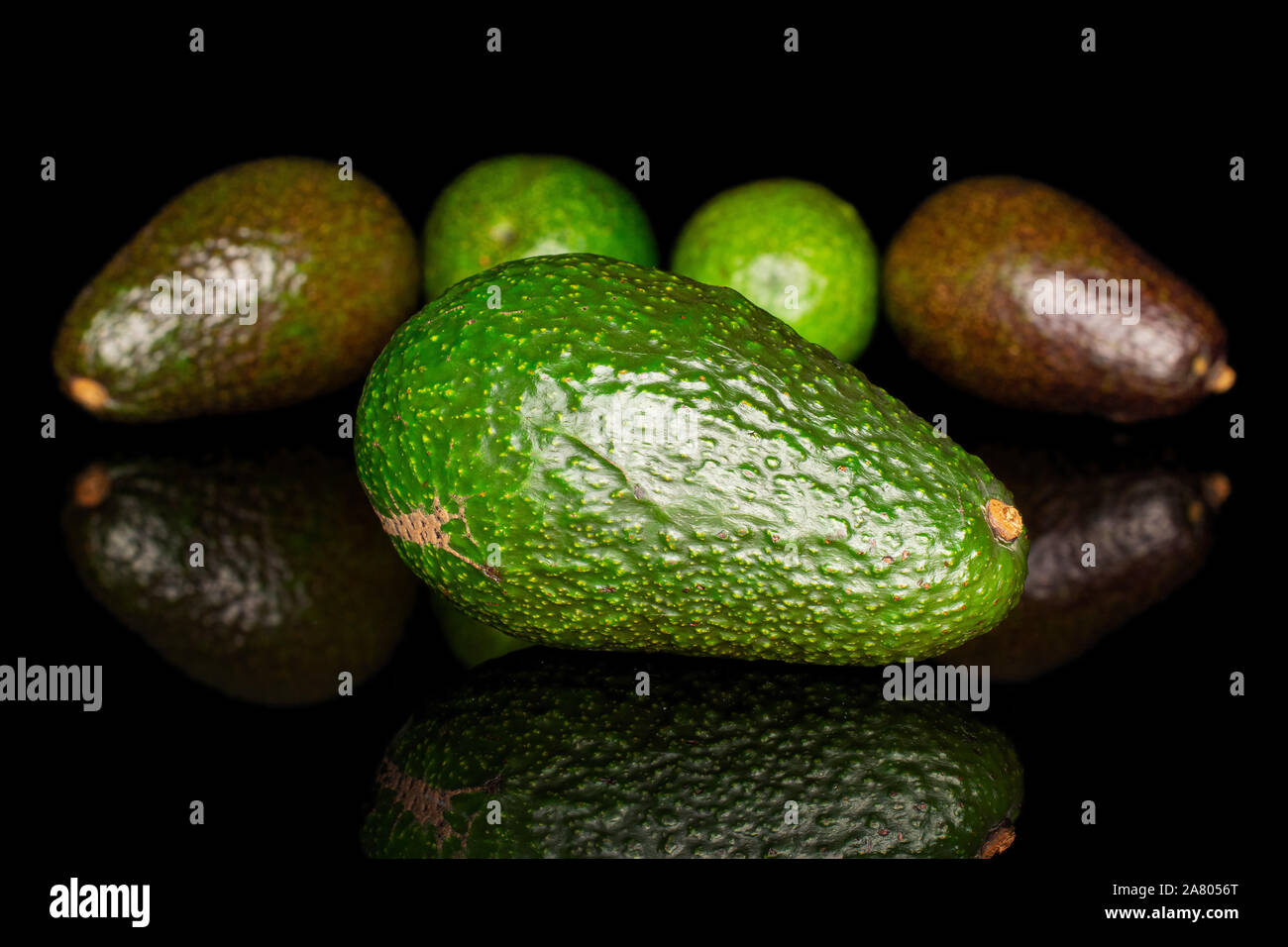 Group of five whole fresh green avocado isolated on black glass Stock ...
