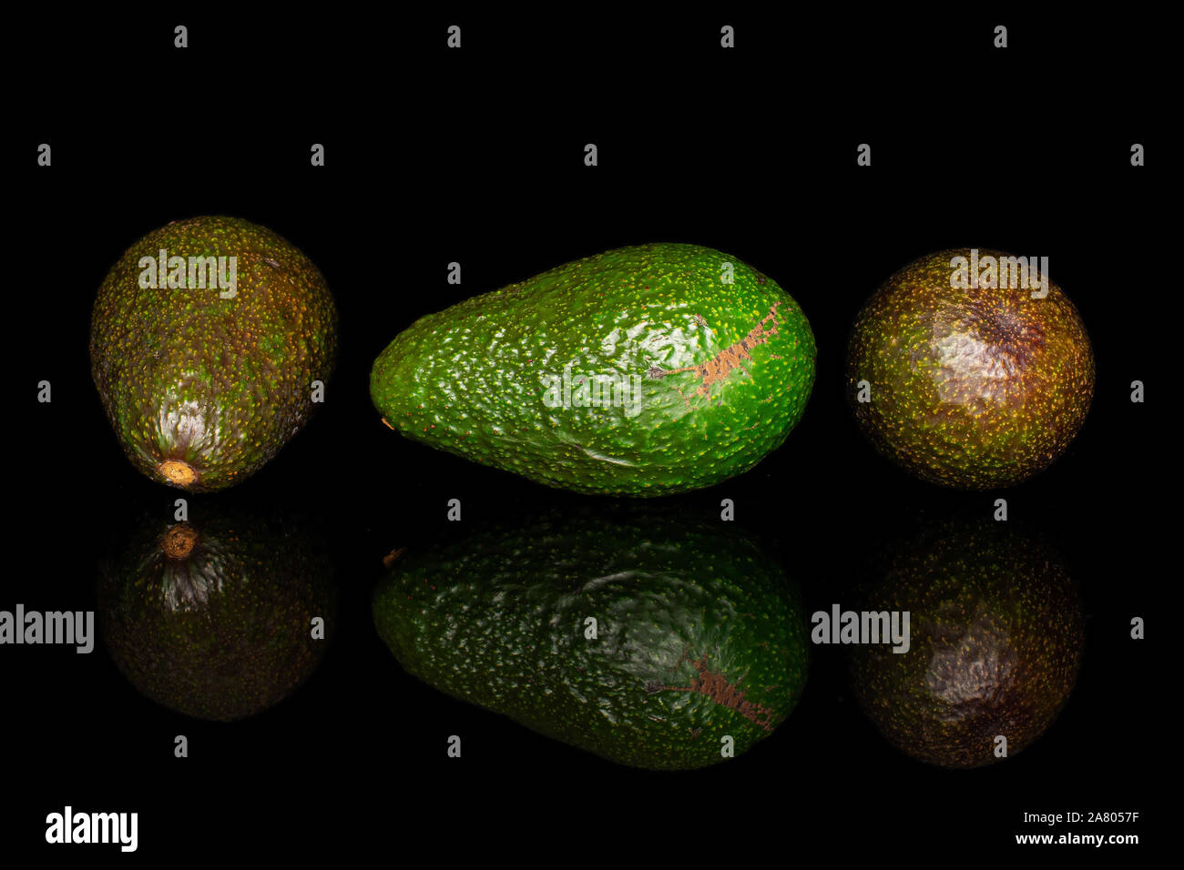 Group of three whole fresh green avocado isolated on black glass Stock ...