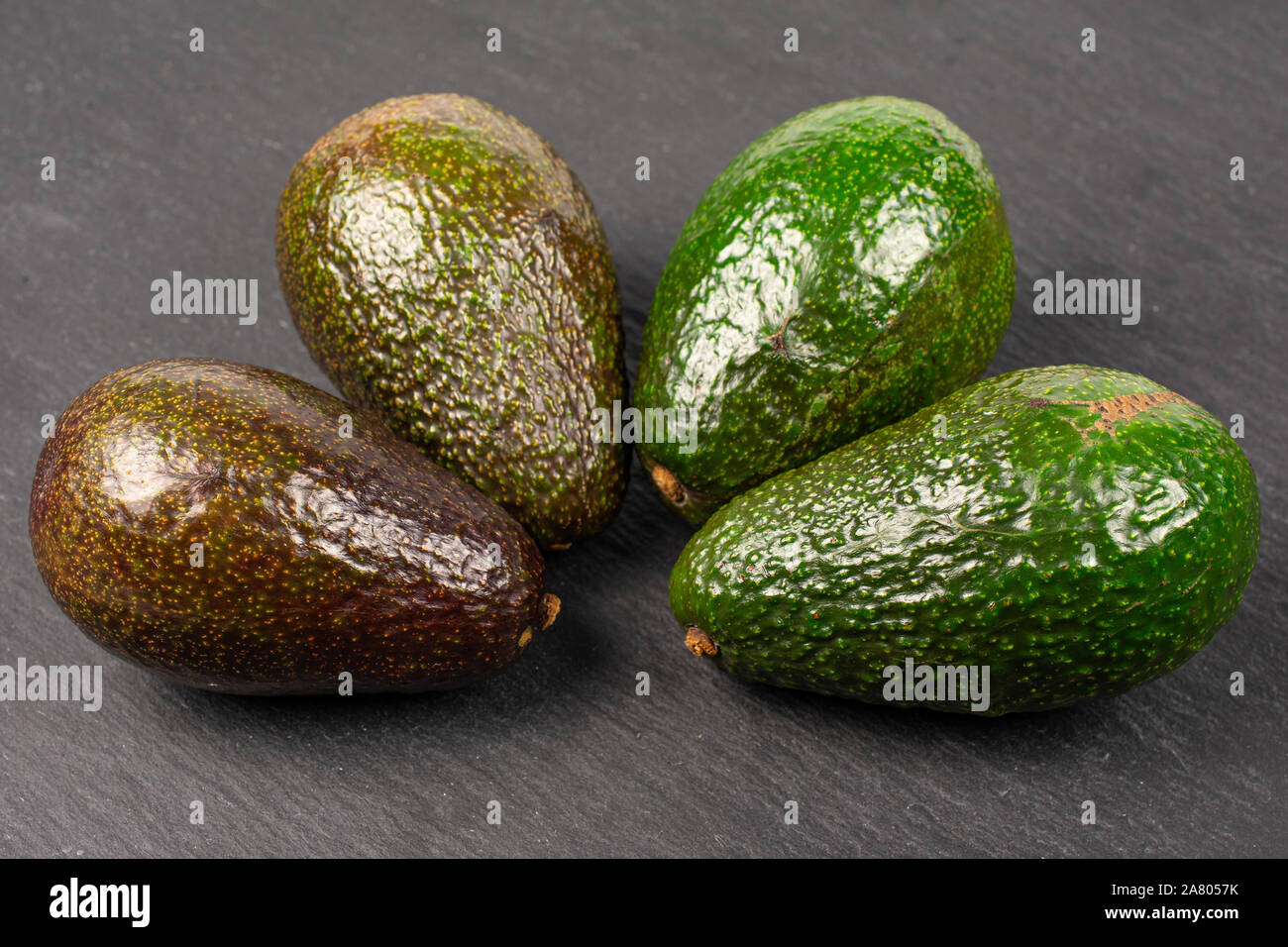 Group of four whole fresh green avocado on grey stone Stock Photo - Alamy