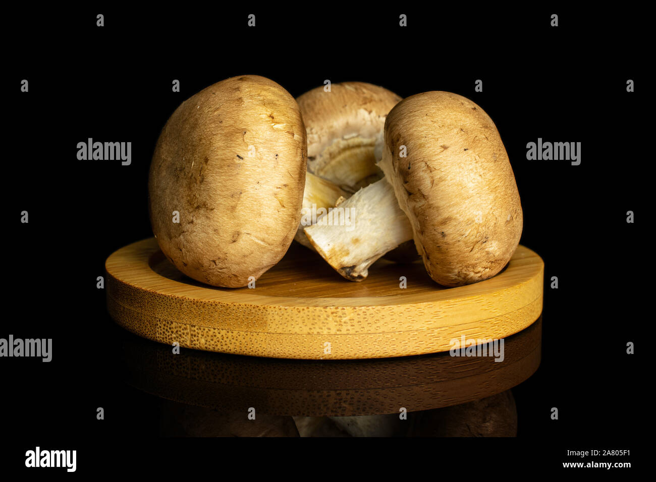 Group of three whole fresh brown champignon on bamboo coaster isolated ...