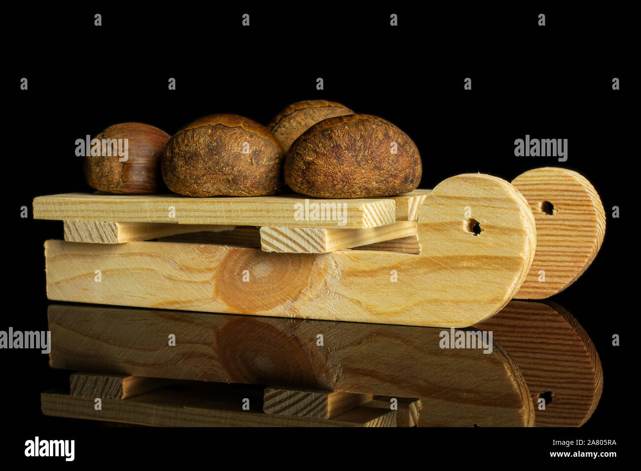 Group of four whole sweet brown chestnut with wooden sledge isolated on ...