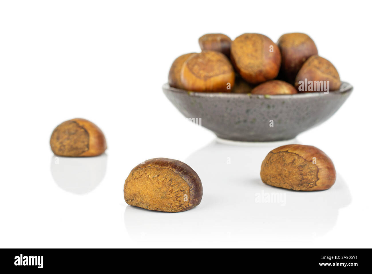 Lot of whole sweet brown chestnut in dark ceramic bowl isolated on ...