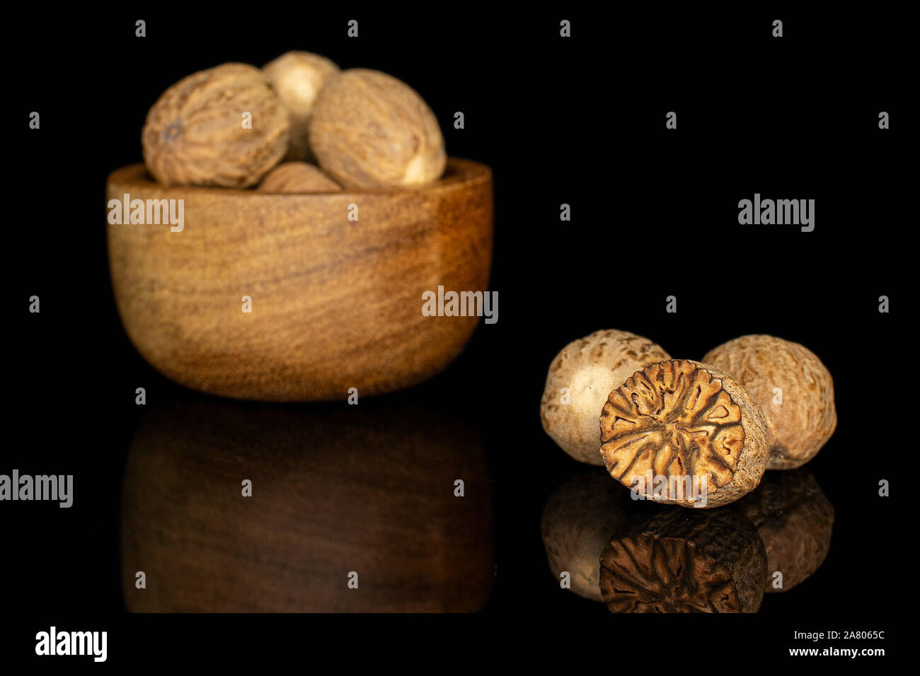 Group of six whole one half of dry brown nutmeg in tiny wooden bowl ...
