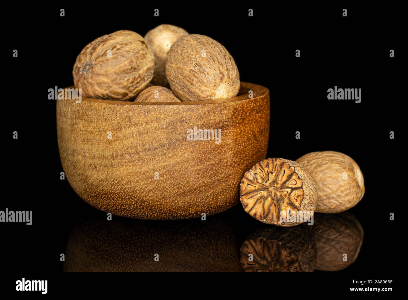 Group of five whole one half of dry brown nutmeg in tiny wooden bowl ...