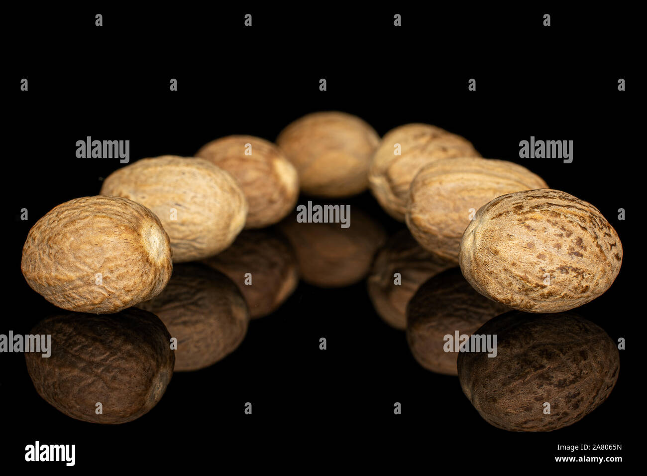 Group of seven whole dry brown nutmeg isolated on black glass Stock ...