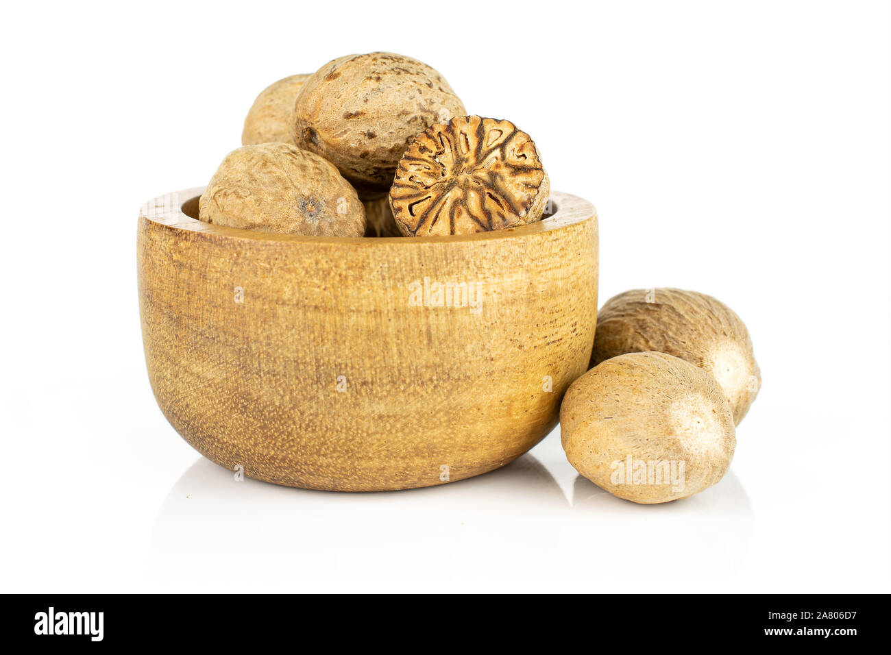 Group of five whole one half of dry brown nutmeg in tiny wooden bowl ...