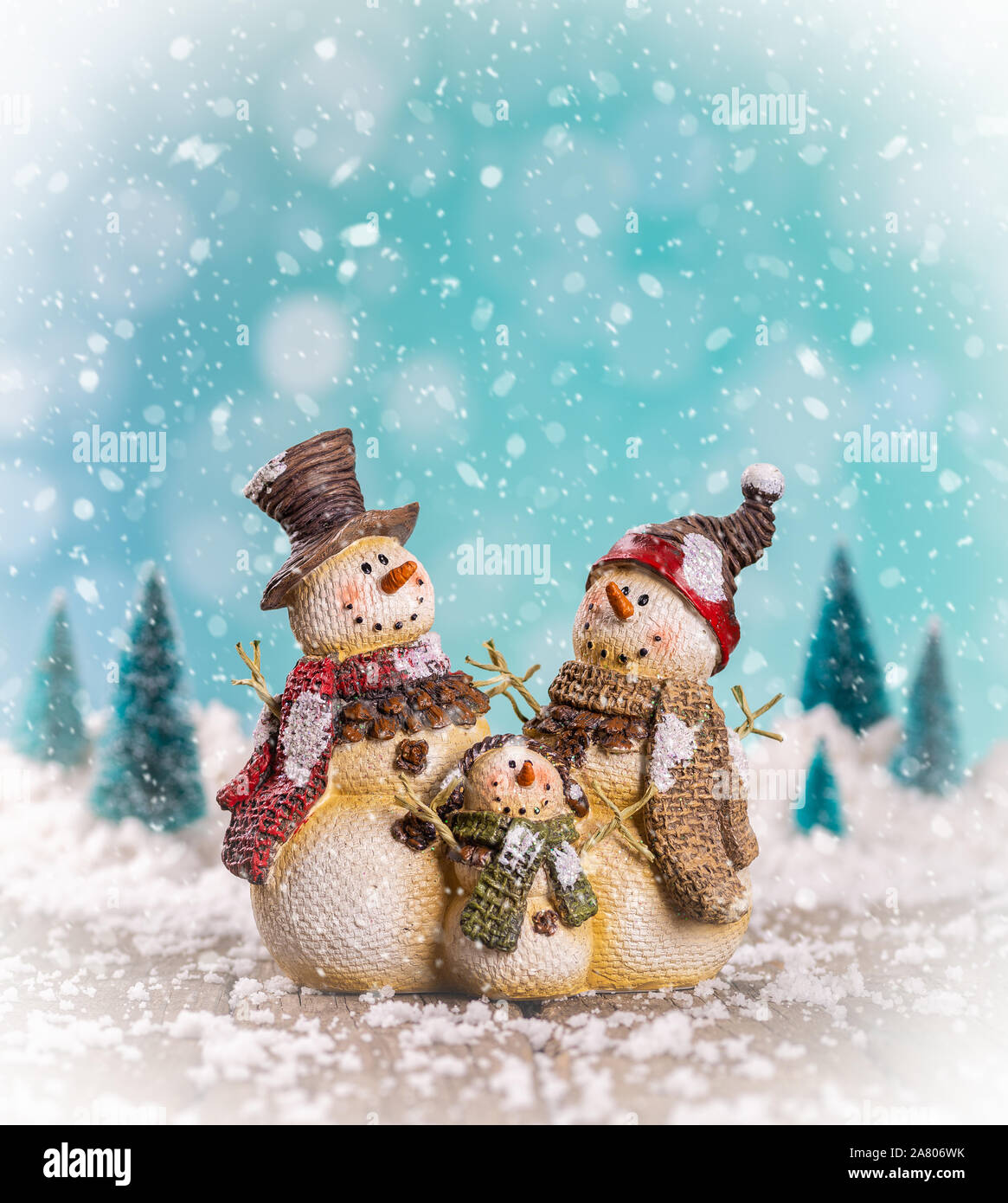 Winter scene of snowmen figurine with falling snow on a bright ...