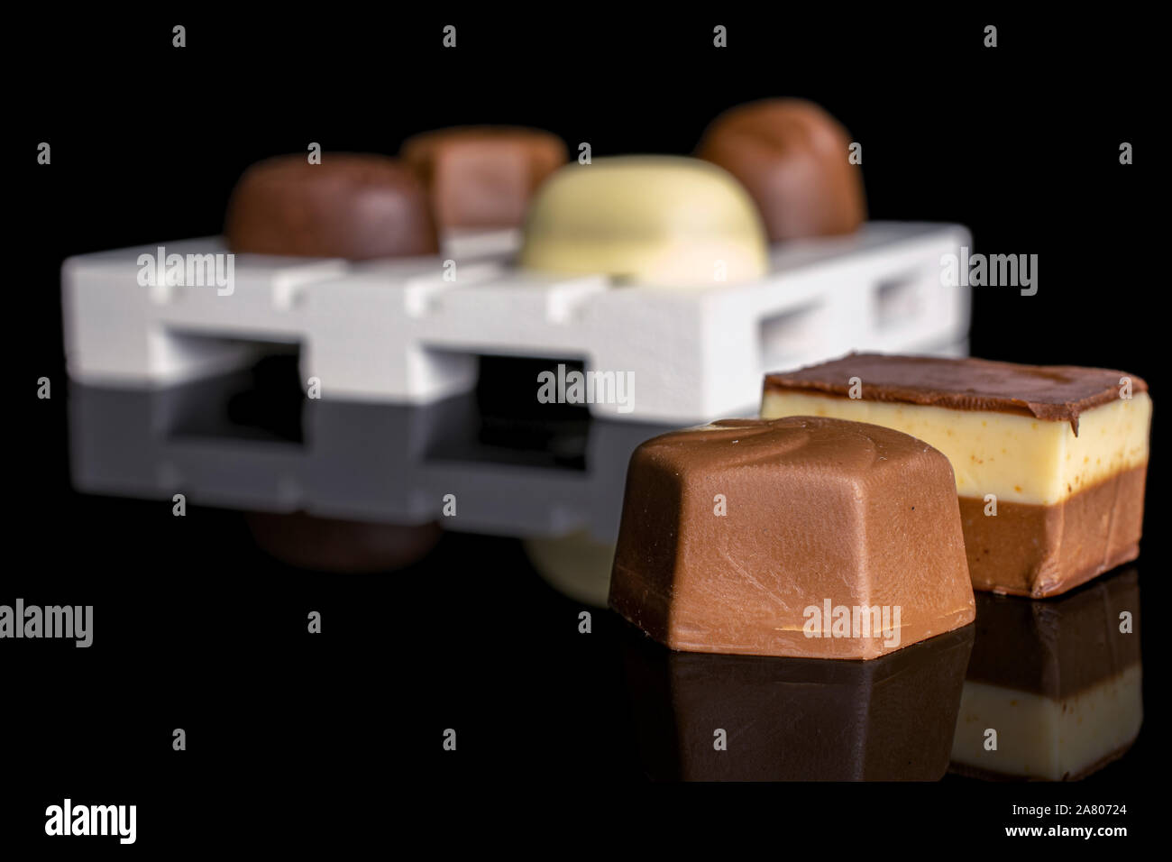 Group of six whole delicious chocolate praline on white wooden pallet ...