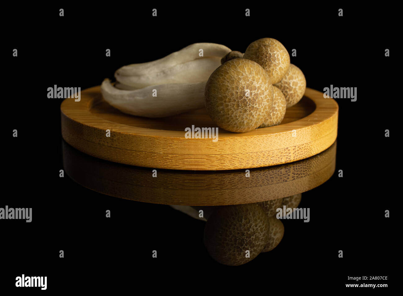 Group of four whole fresh brown buna shimeji mushroom on bamboo coaster ...