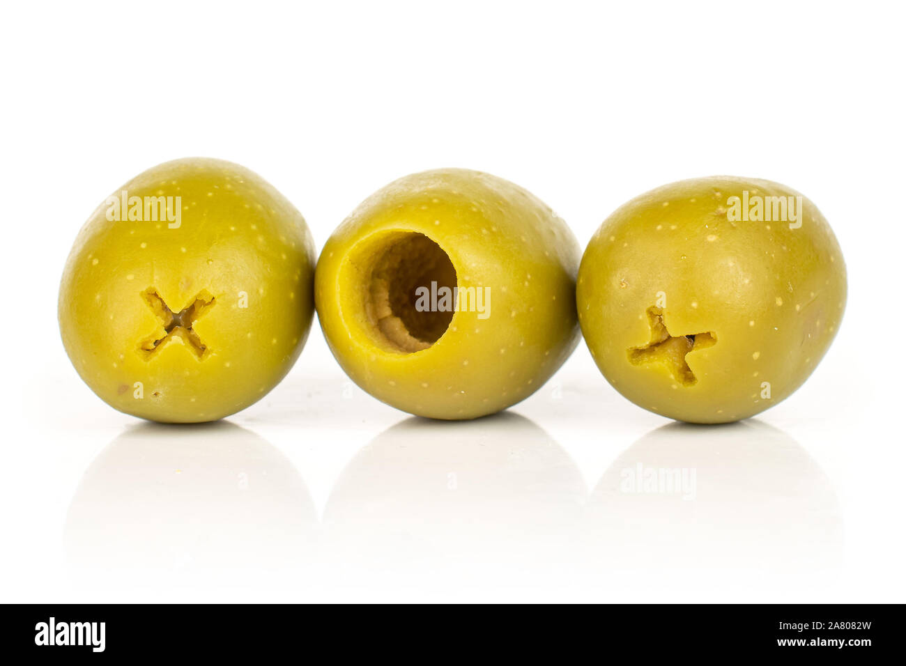 Group of three whole pitted green olive in row isolated on white ...