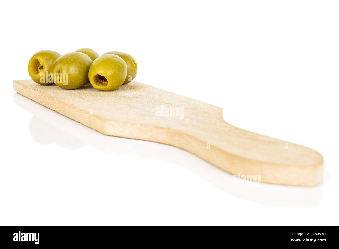 Group of five whole pitted green olive on small wooden cutting board ...