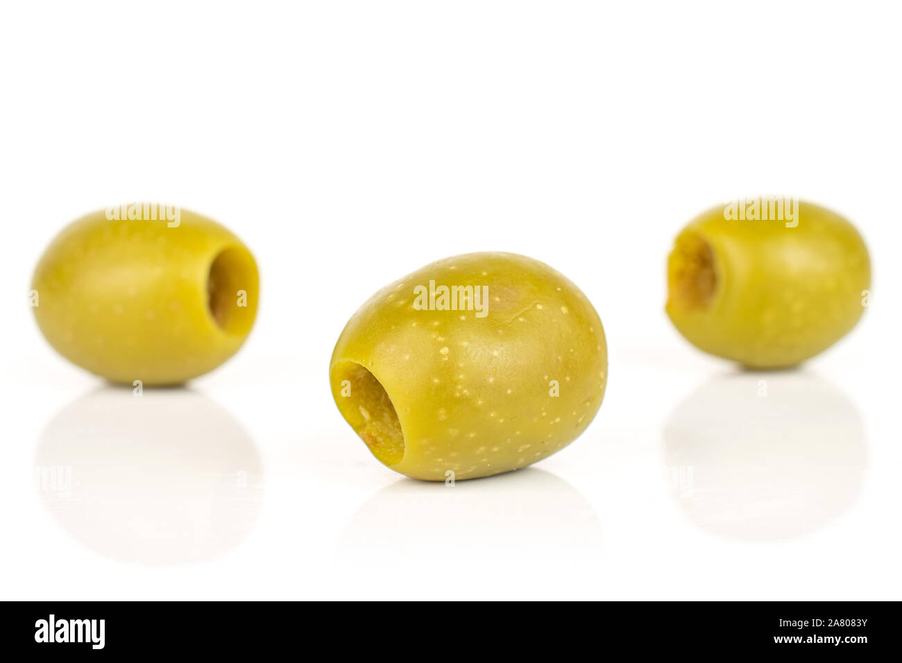 Group of three whole pitted green olive isolated on white background ...