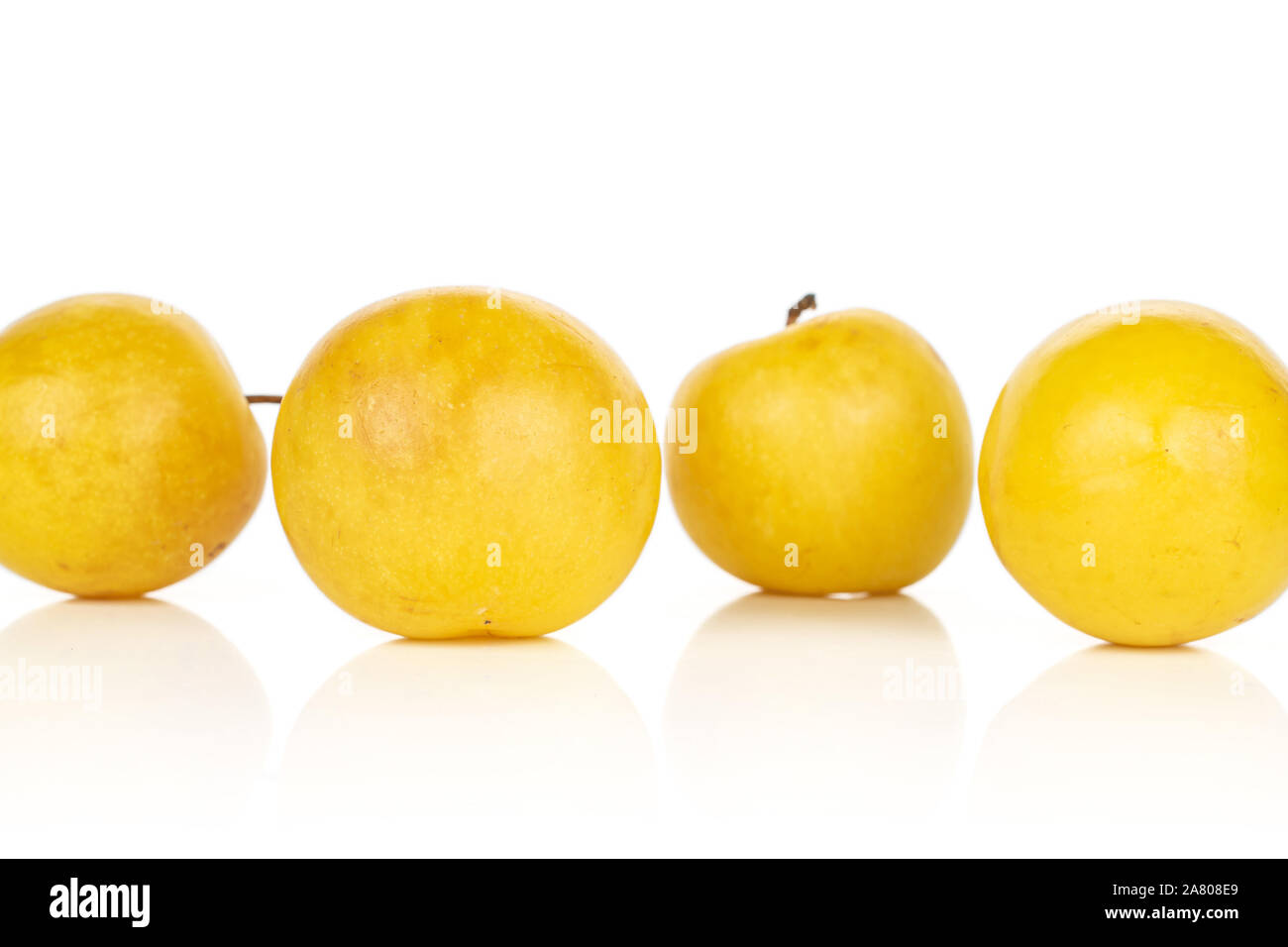 Group of four whole fresh yellow plum isolated on white background ...