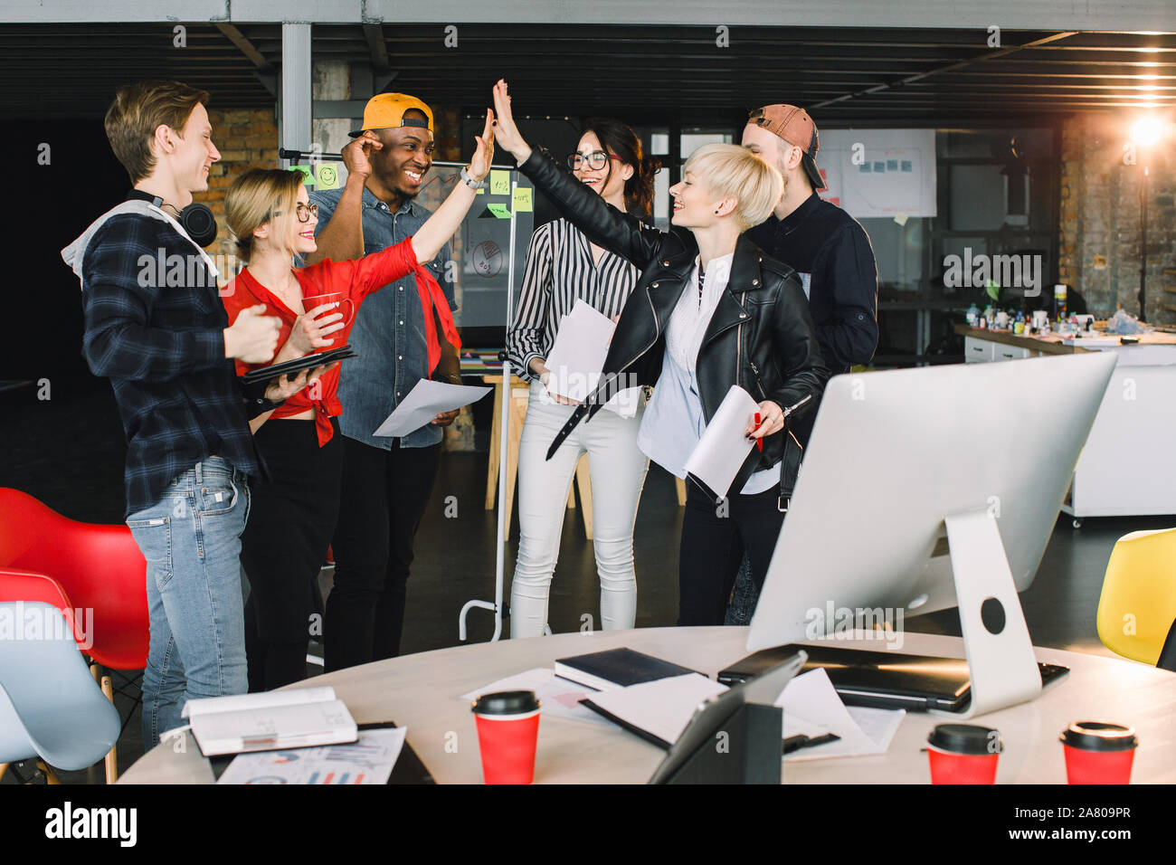 Happy young multiethnic business people celebrating success at company ...