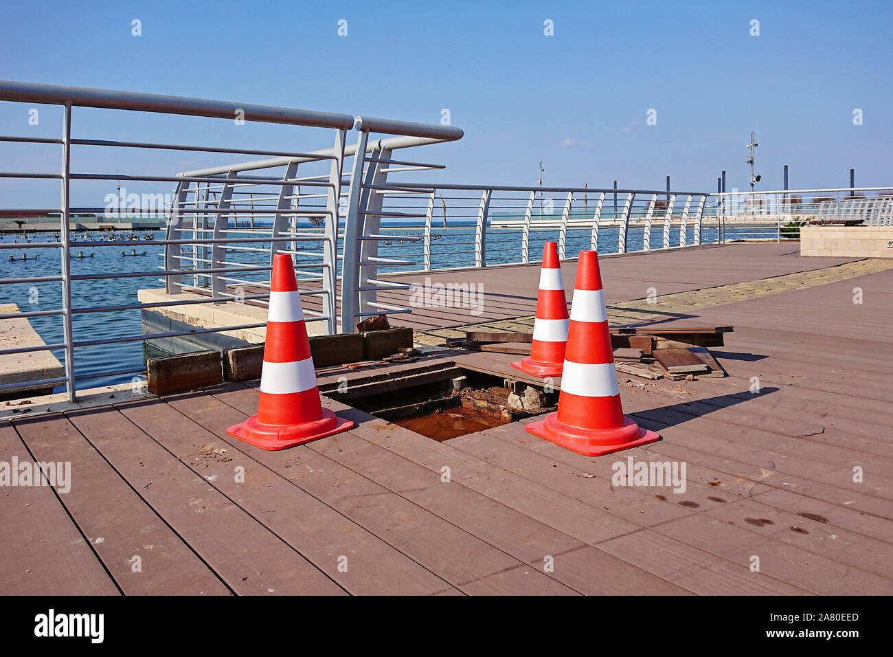 Three traffic cones standing on boundary of open hatch. Sign of ...