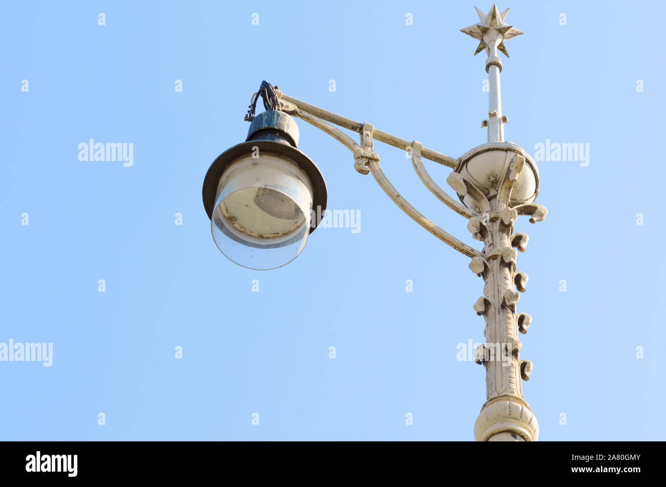 Ornate vintage white painted wrought iron lamp post viewed from below ...