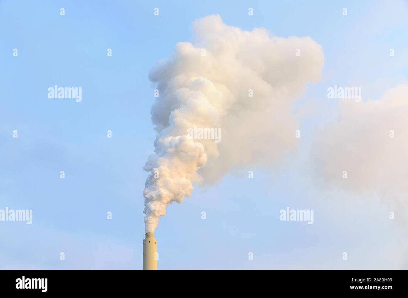 Smoke billowing from an industrial chimney into a smoky sky in a ...