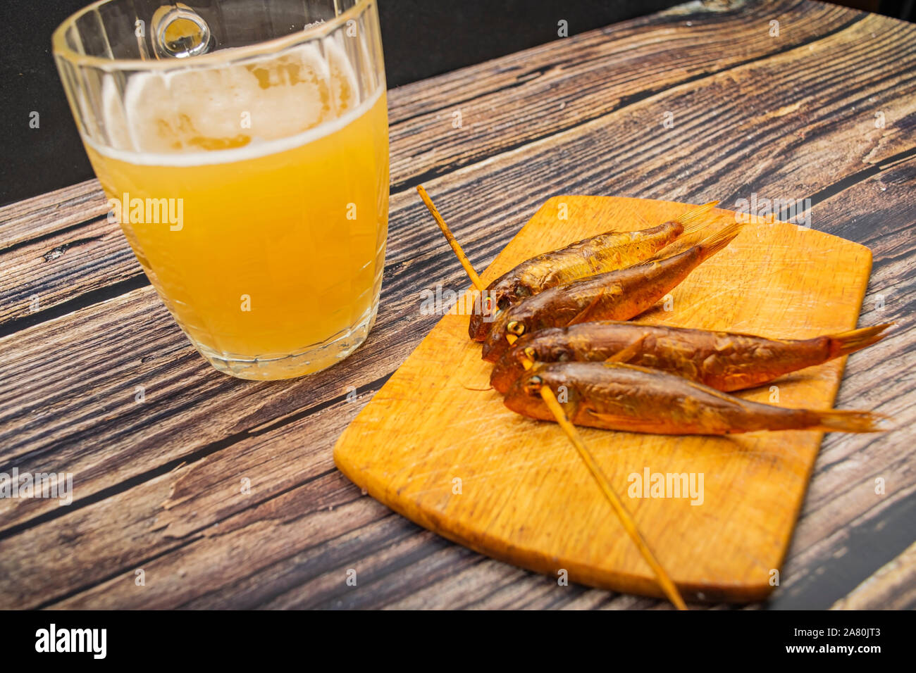 Dried mullet on a wooden Board with a mug of beer on the table. Fish ...