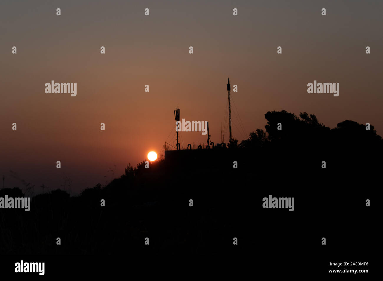 sun setting behind TV antennas creating a nice contrast Stock Photo - Alamy