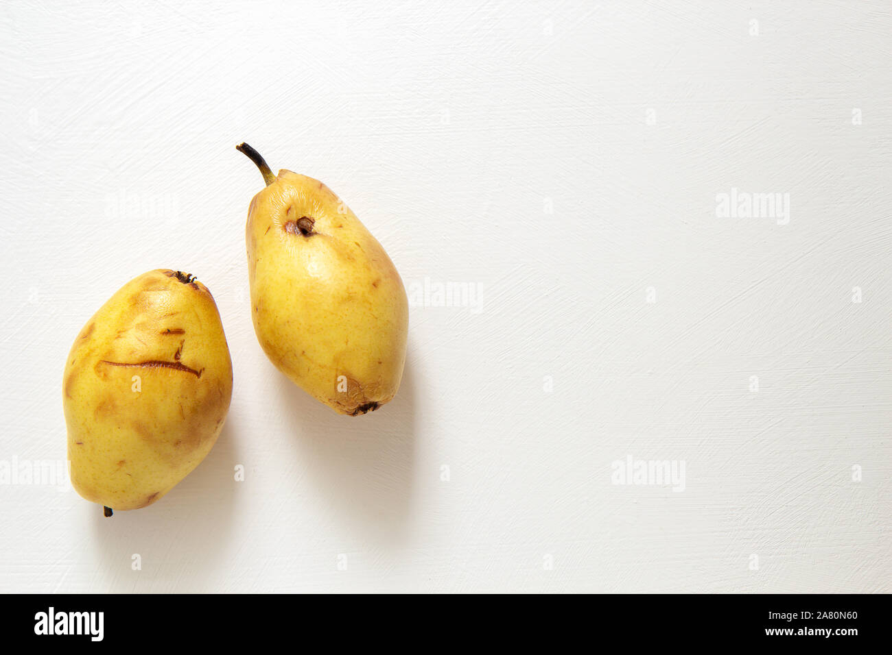 Ugly food. Two spoiled old yellow pears on a white background ...
