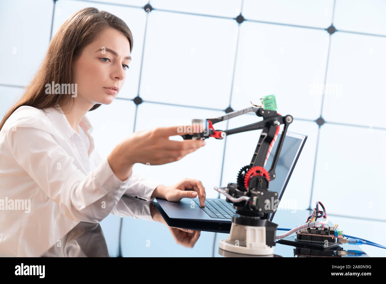 A young woman writes an algorithm for the robot arm. Science Research ...