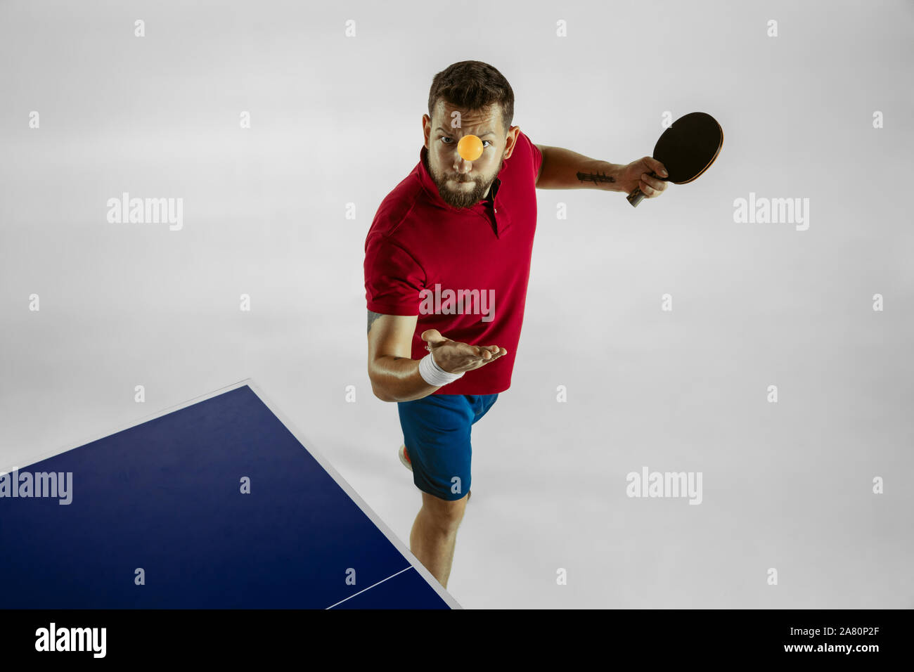 Young man plays table tennis on white studio background. Model in ...