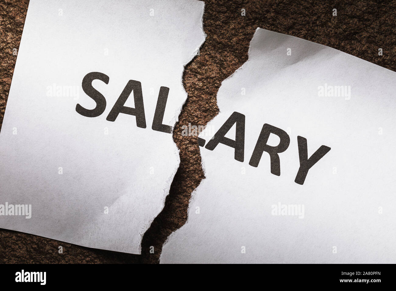 Sheet with the words salary, torn in half. Concept on the financial ...