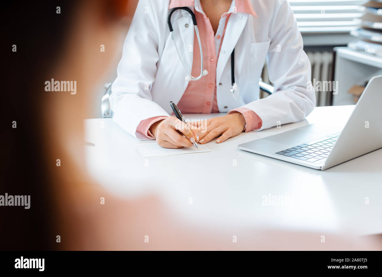 Close-up of doctor taking notes while having appointment with patient ...