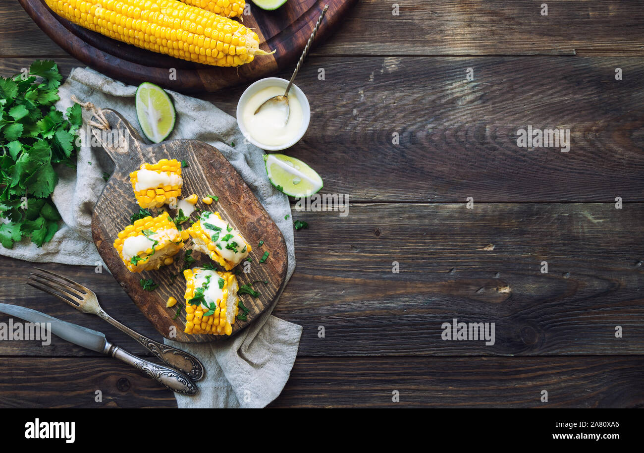 Fresh baked corn cobs with aioli sauce and cilantro on rustic wooden ...