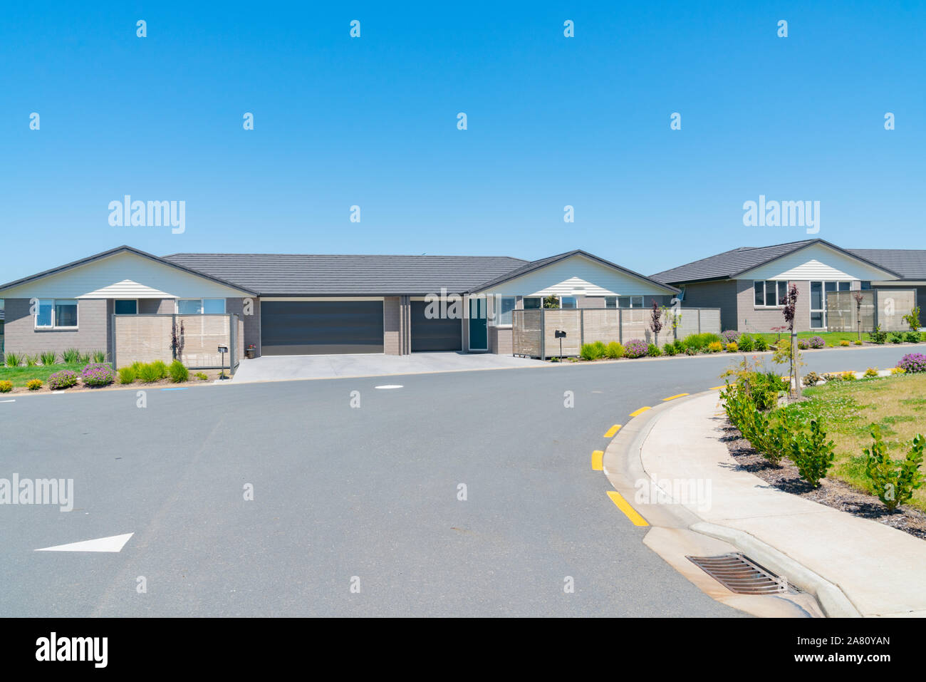 New subdivision street with uniform homes and front gardens lining both ...