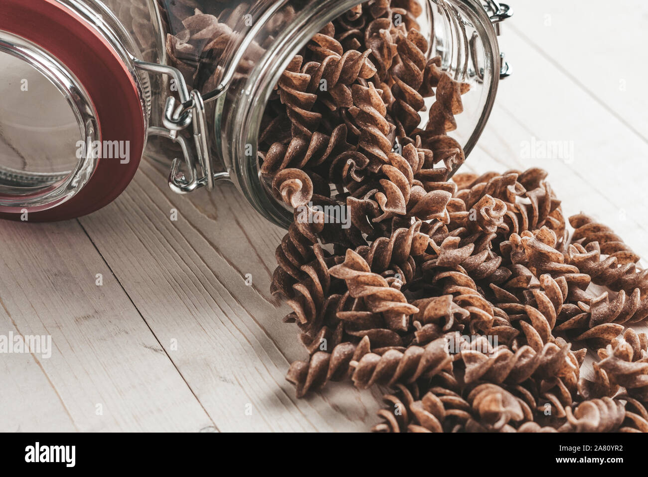 Tilted glass jar with pasta on the table Stock Photo - Alamy