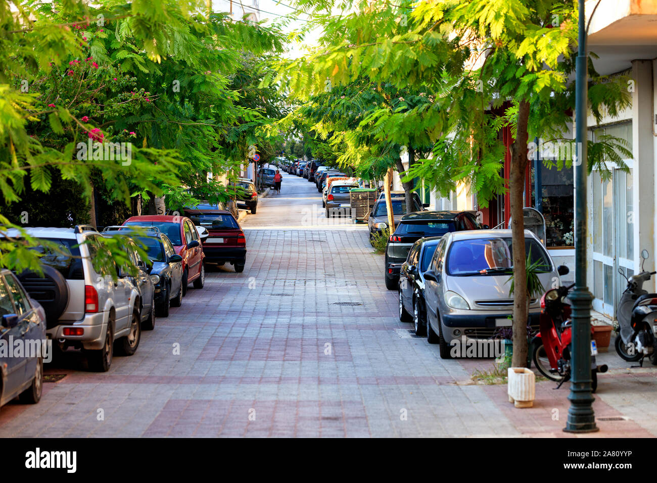 A large number of cars clutter the pedestrian sidewalks of a narrow ...