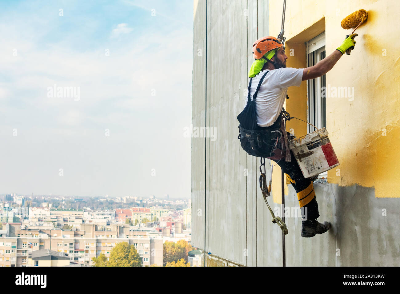 Industrial rope access worker hanging from the building while painting ...