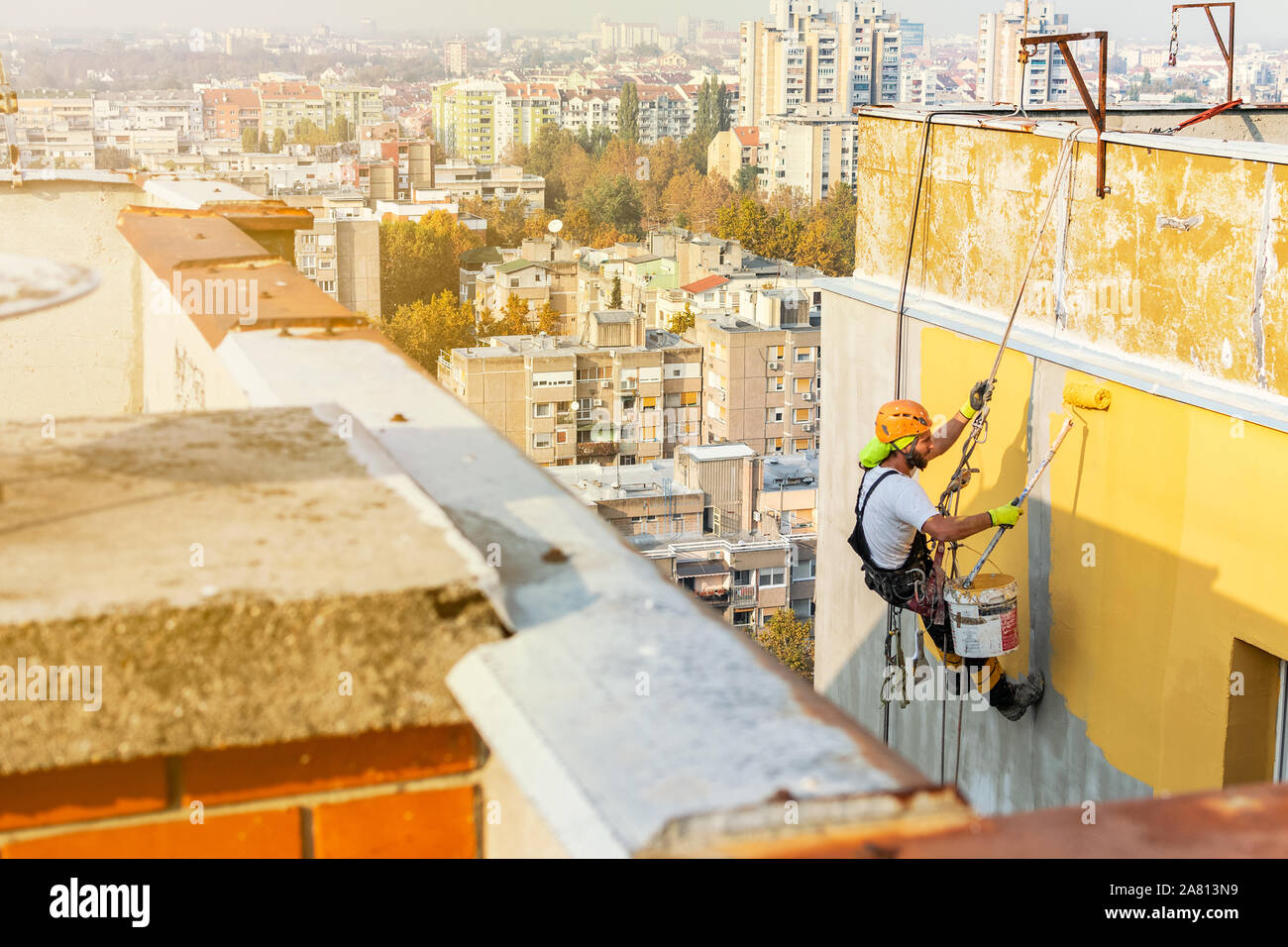 Industrial rope access worker hanging from the building while painting ...